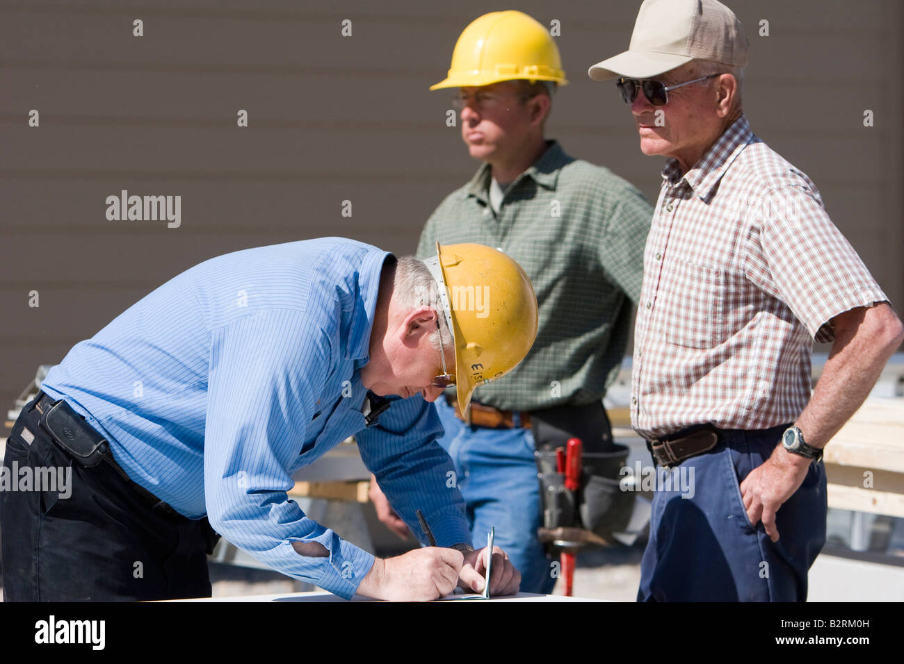 A construction foreman signs paperwork on a job site Stock Photo - Alamy