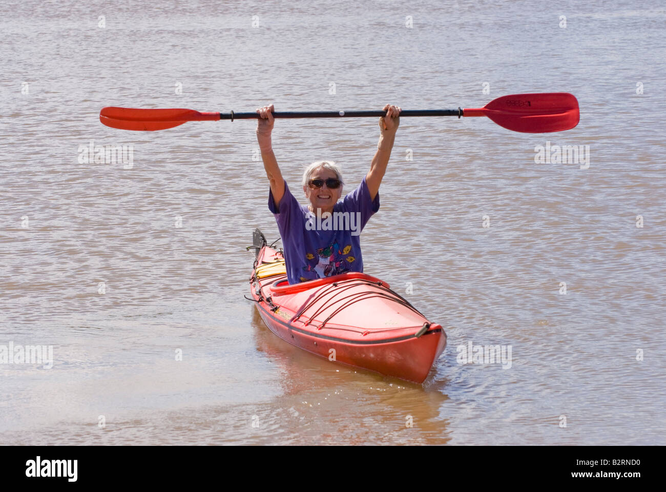 Mature woman in kayak with paddle in air Stock Photo - Alamy