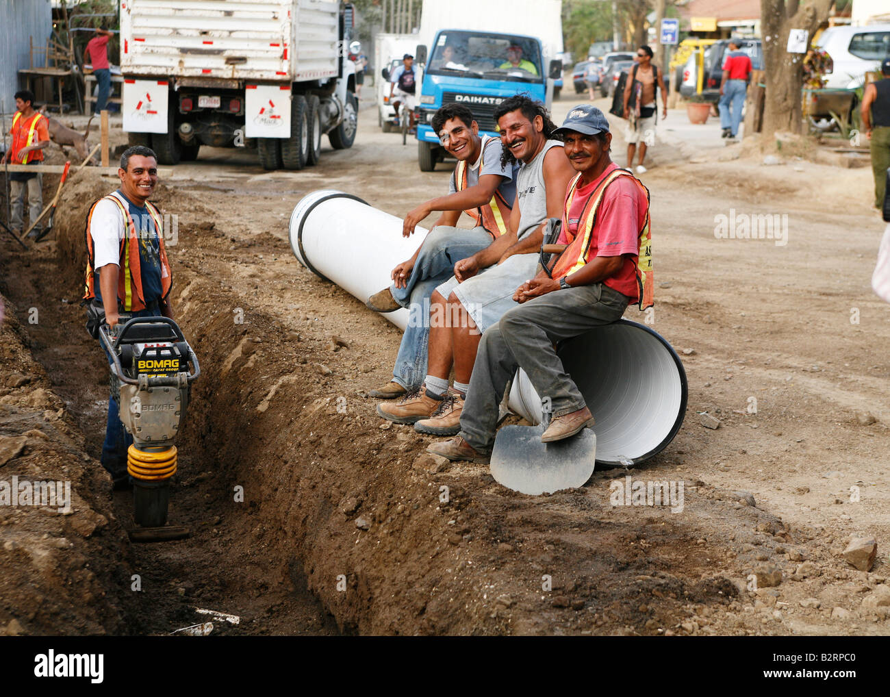 Municipal road workers and supervisor install part of a new storm drain ...