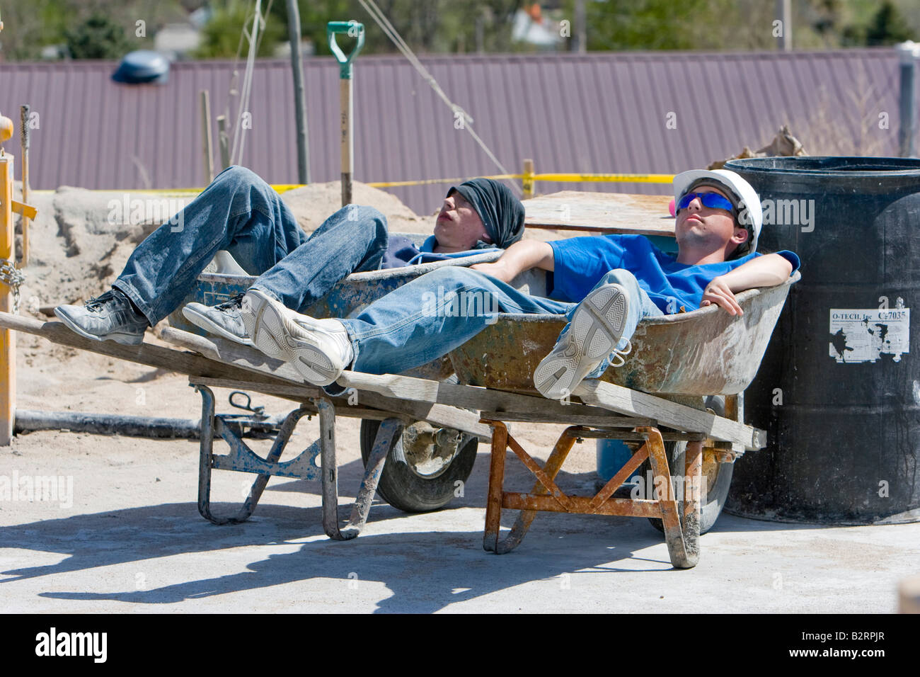 Two construction workers napping in a wheelbarrow Stock Photo - Alamy