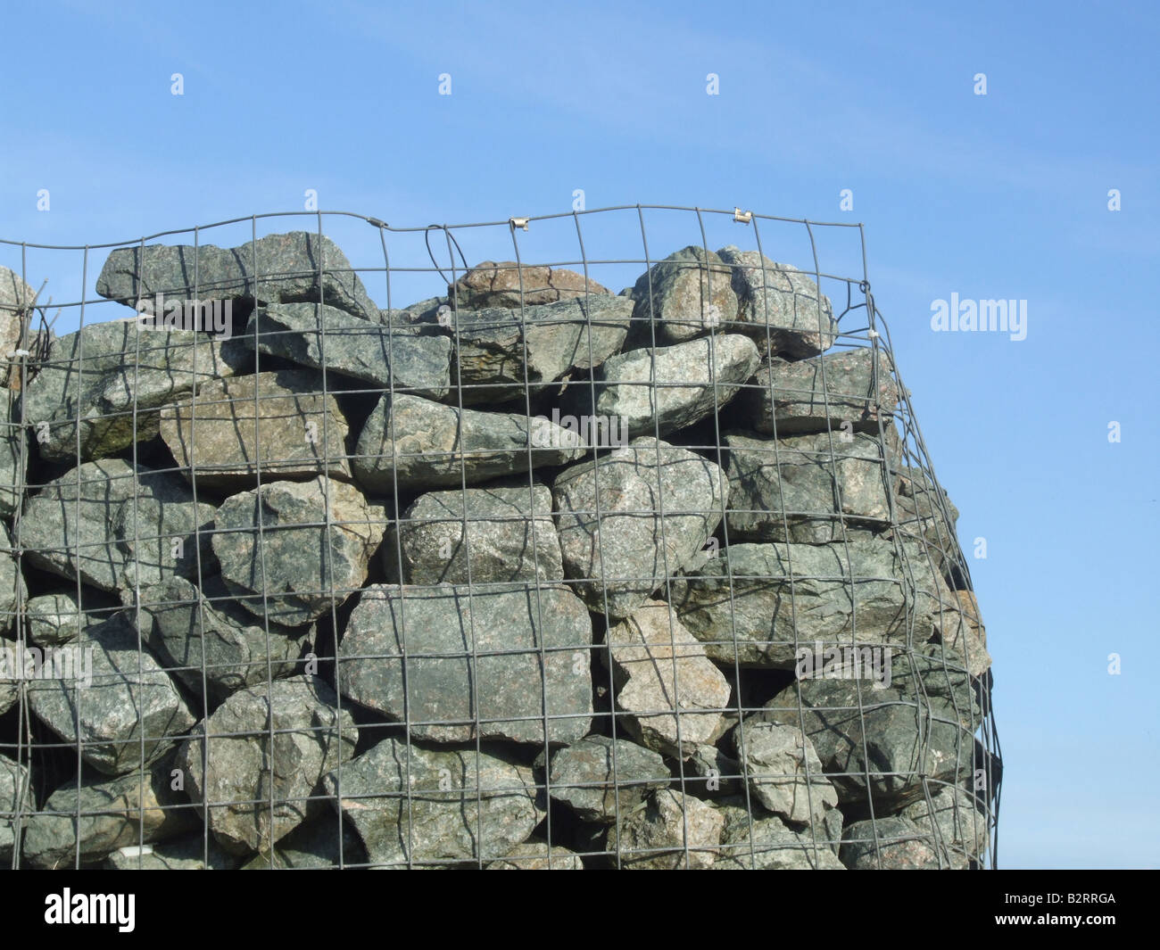 pile of rocks supported in a steel wire mesh Stock Photo - Alamy