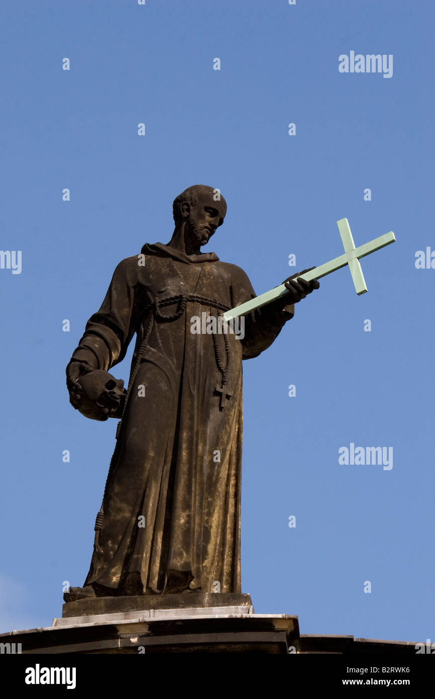 A monk statue holds a crucifix on the top of the Hofkirche in Dresden ...