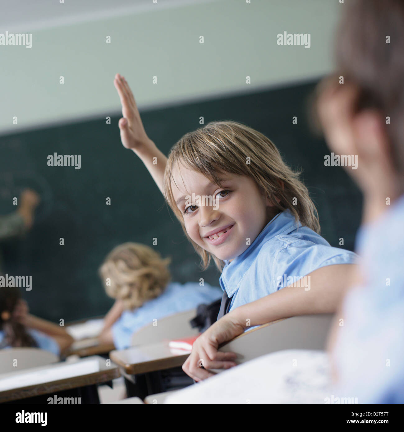 School boy raising hand in class Stock Photo - Alamy