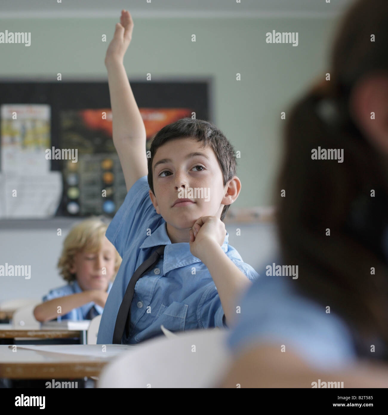 School boy raising hand in class Stock Photo - Alamy