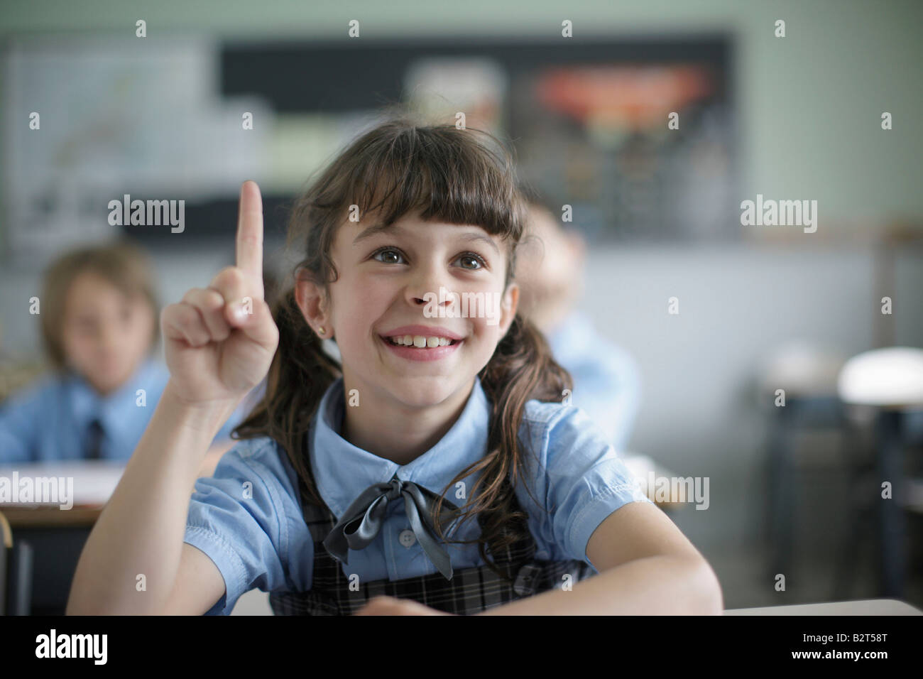 School girl raising hand in class Stock Photo - Alamy