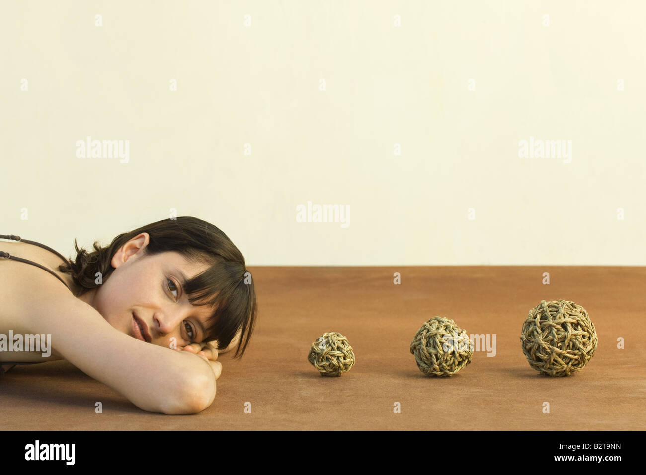 Woman resting head on arms in front of string balls, smiling at camera ...