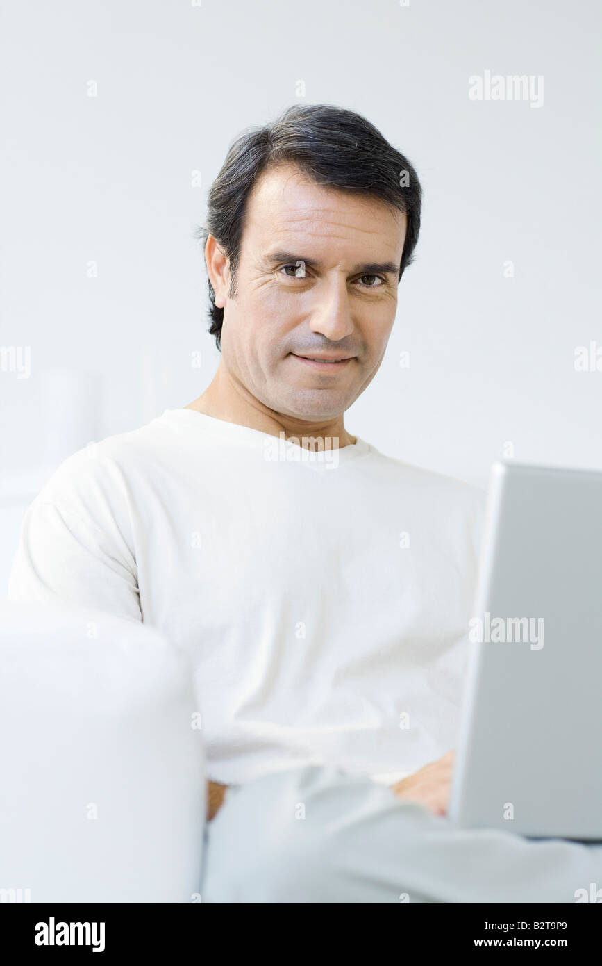 Man holding laptop, smiling at camera, portrait Stock Photo - Alamy