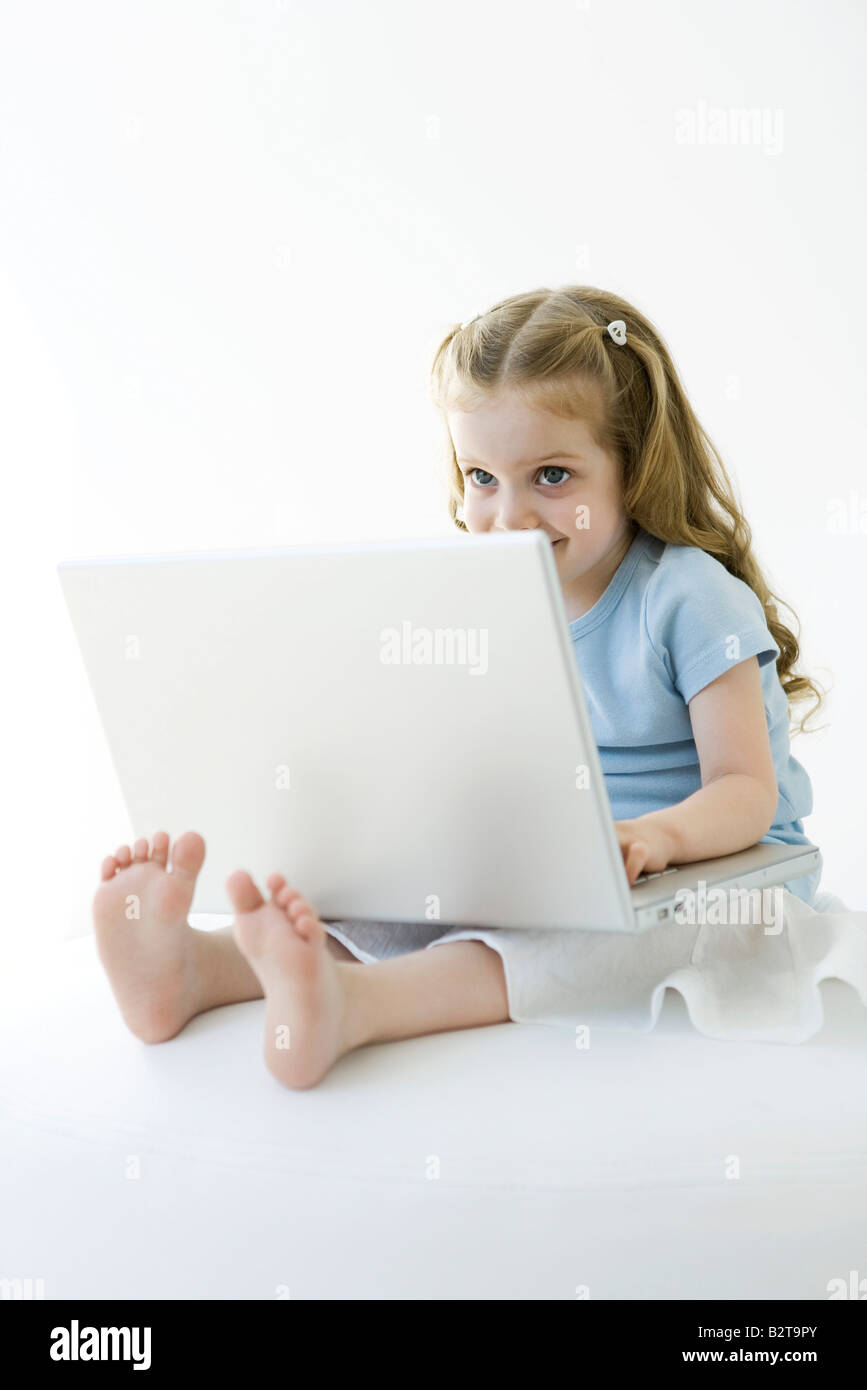 Little girl sitting on the ground, using laptop computer Stock Photo ...