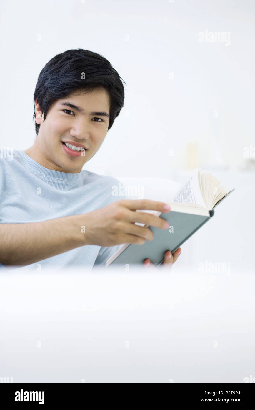 Man smiling at camera, holding book Stock Photo - Alamy
