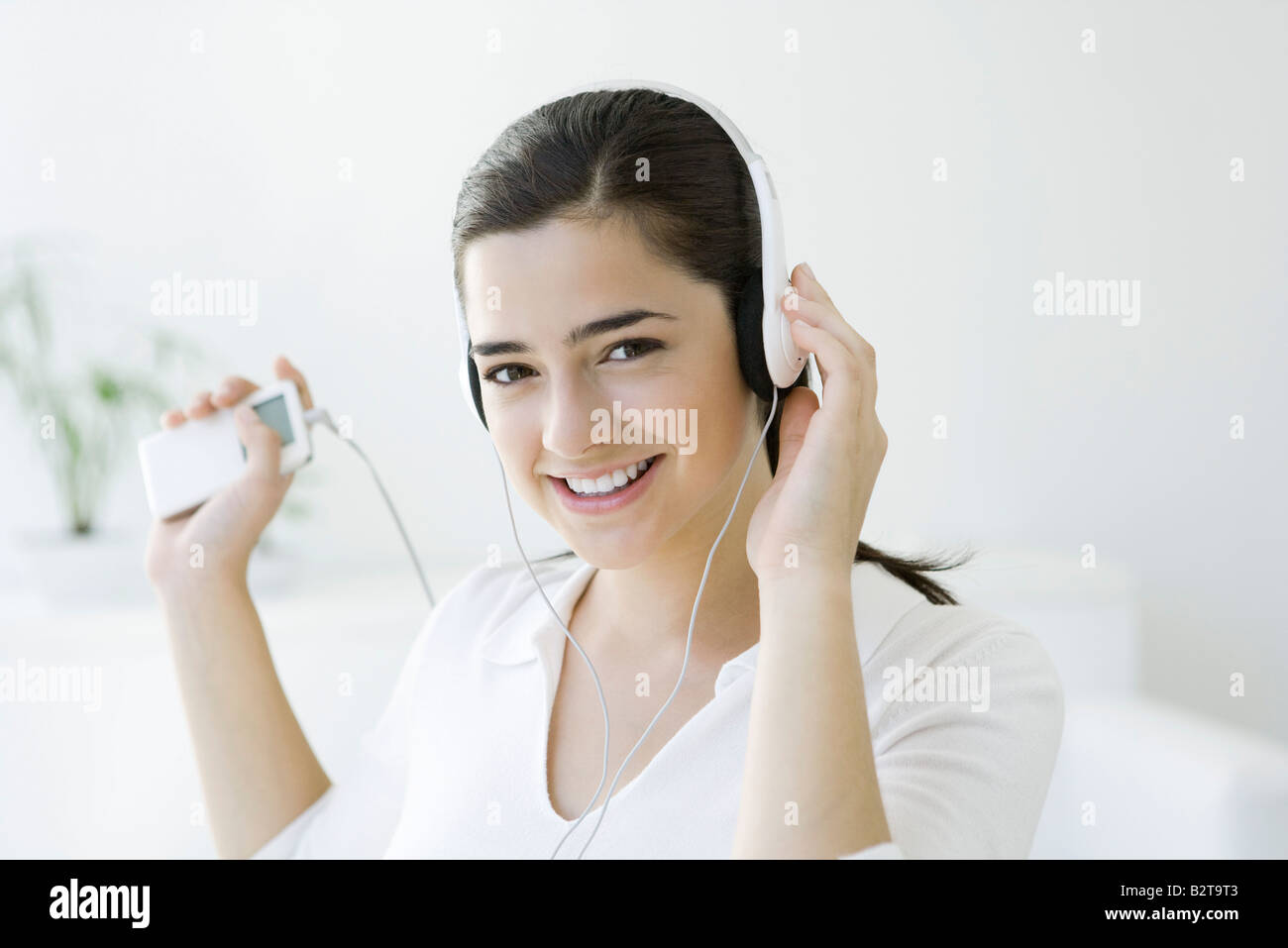 Woman listening to MP3 player with headphones, smiling at camera Stock ...
