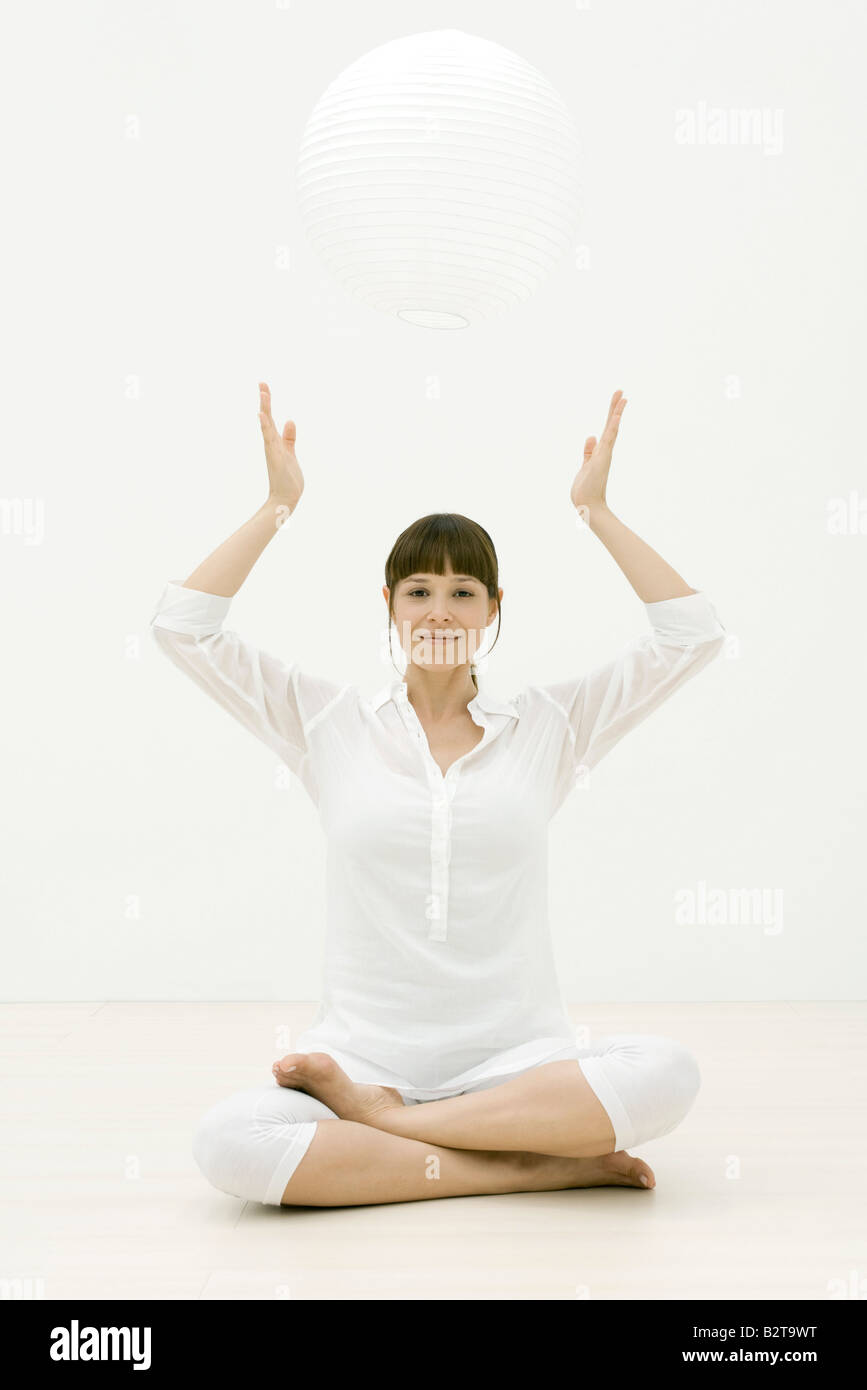 Woman meditating with sphere over head Stock Photo - Alamy