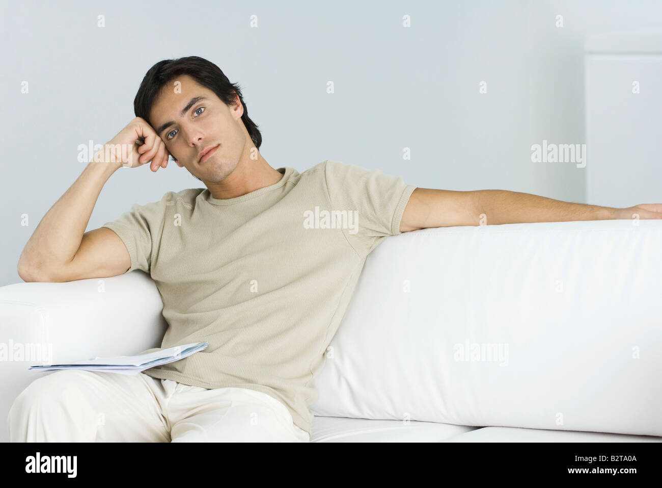 Man relaxing on sofa, looking at camera, leaning on elbow Stock Photo ...