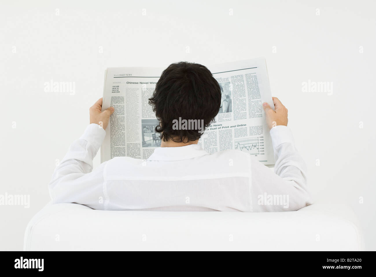 Man sitting in armchair, reading newspaper, rear view Stock Photo - Alamy