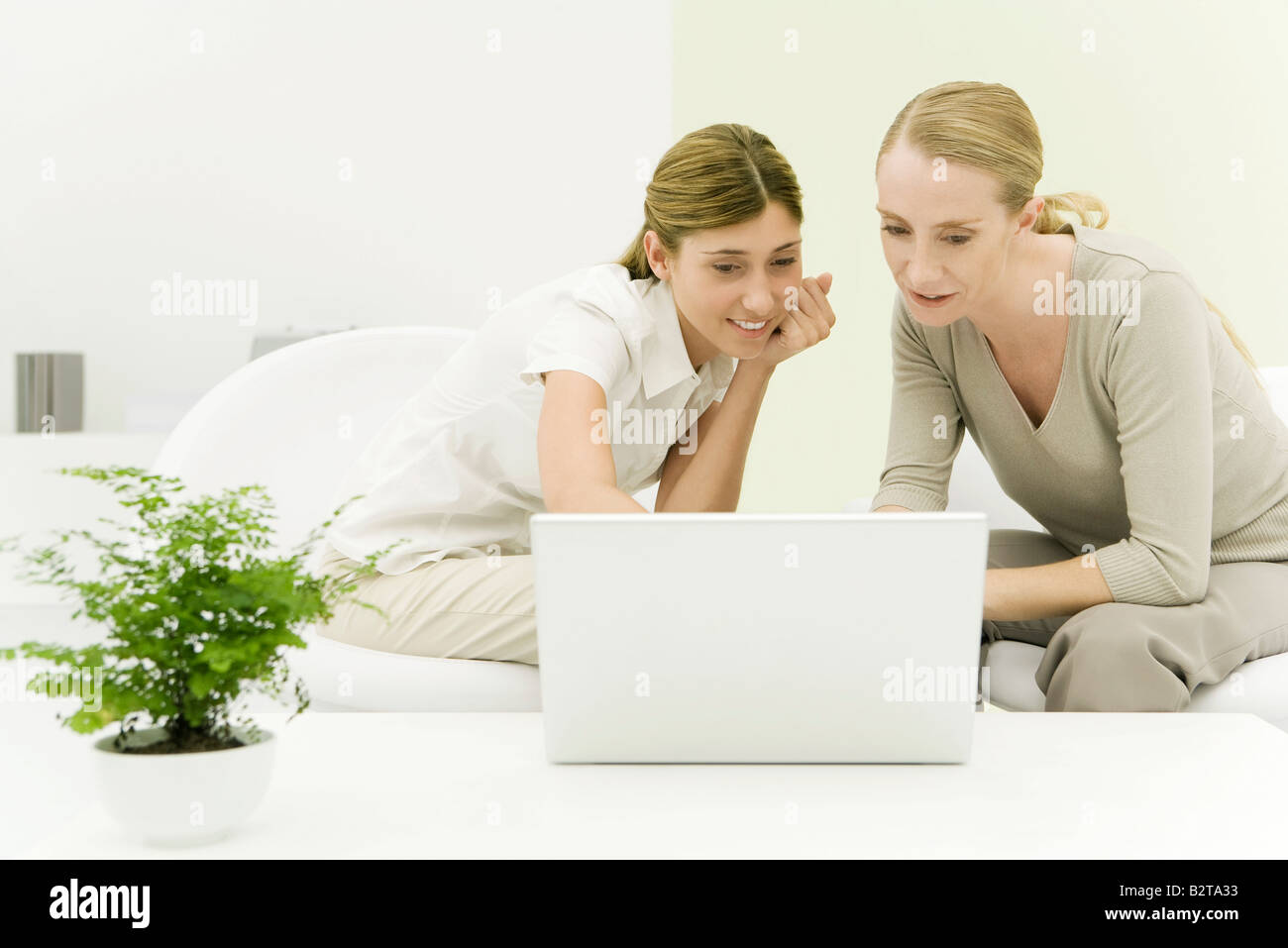 Two women looking at laptop computer together, smiling Stock Photo - Alamy