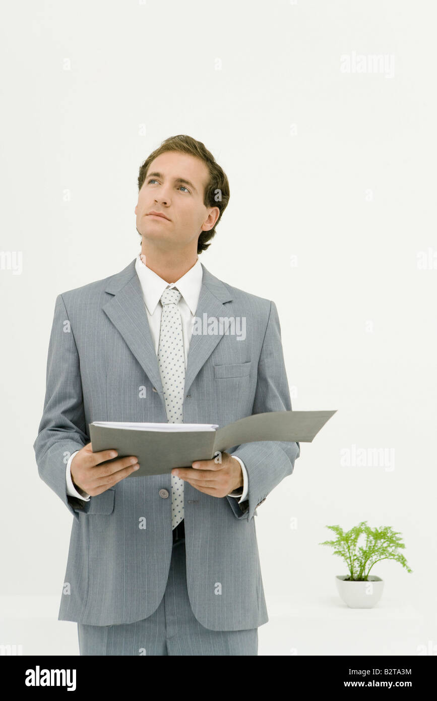 Businessman holding document, looking up Stock Photo - Alamy