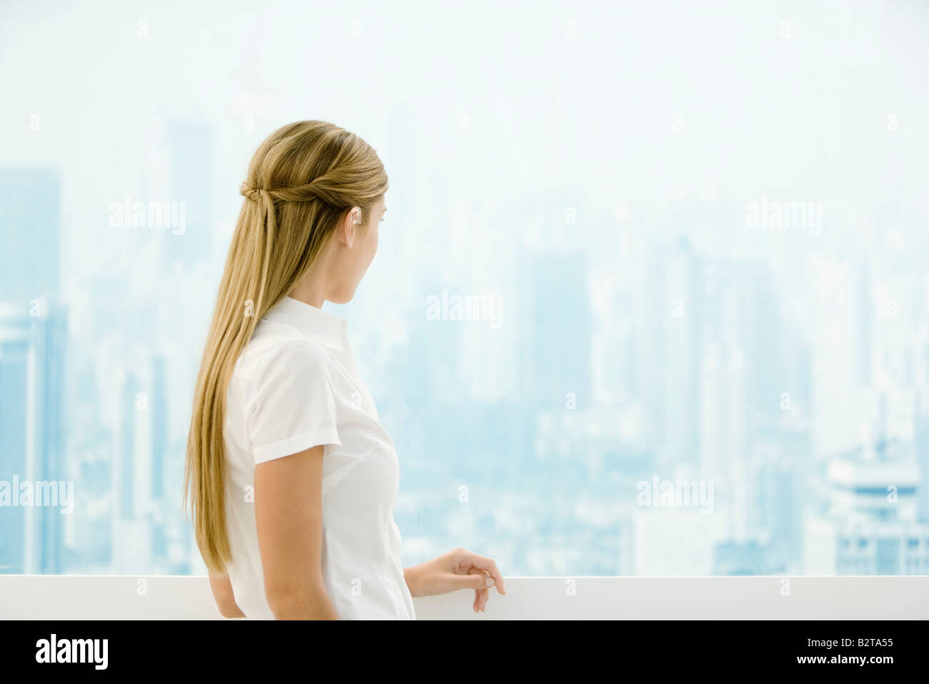 Young woman standing in front window, looking out Stock Photo - Alamy