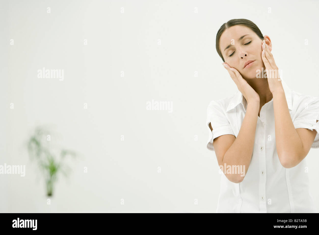Woman holding face, head tilted, eyes closed Stock Photo - Alamy