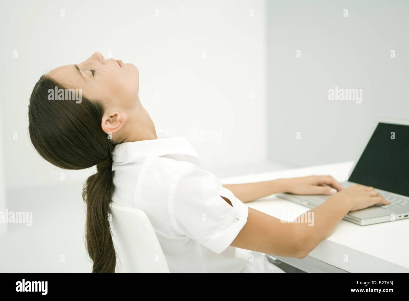 Woman sitting in front of laptop, head back, eyes closed Stock Photo ...