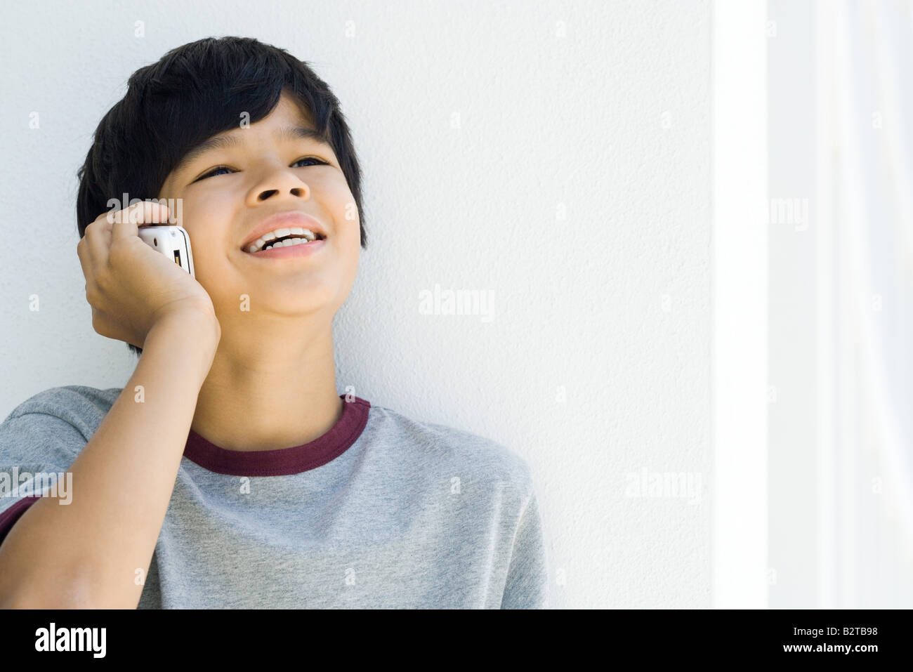 Boy using cell phone, looking up, smiling Stock Photo - Alamy