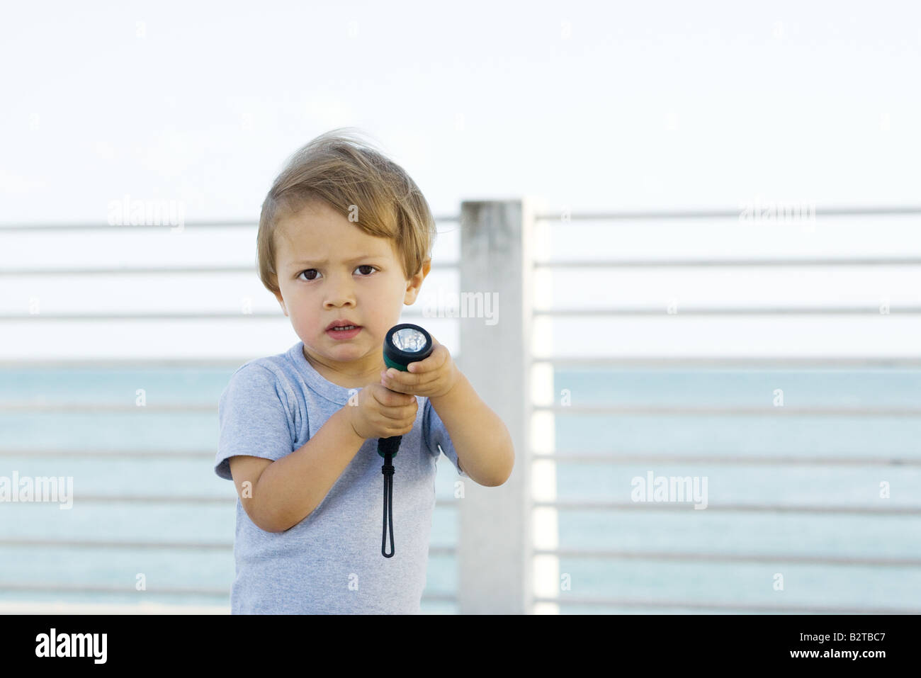 Little boy holding flashlight, frowning at camera Stock Photo - Alamy