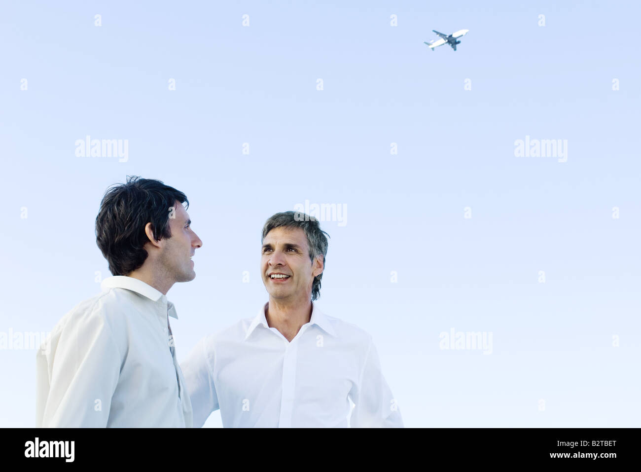 Two men talking to each other, airplane high in the background Stock ...