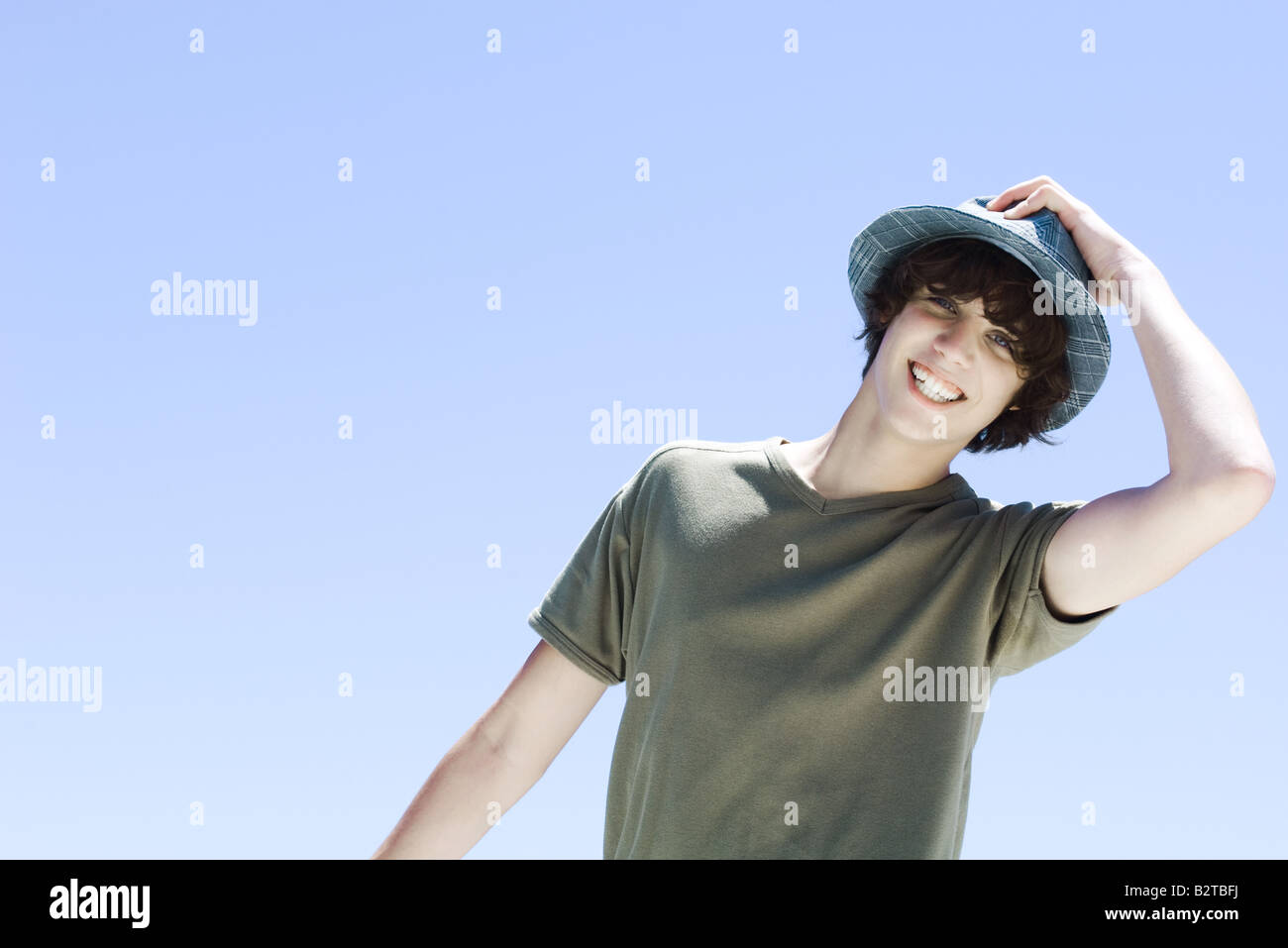 Teenage boy smiling at camera, putting on a hat Stock Photo - Alamy