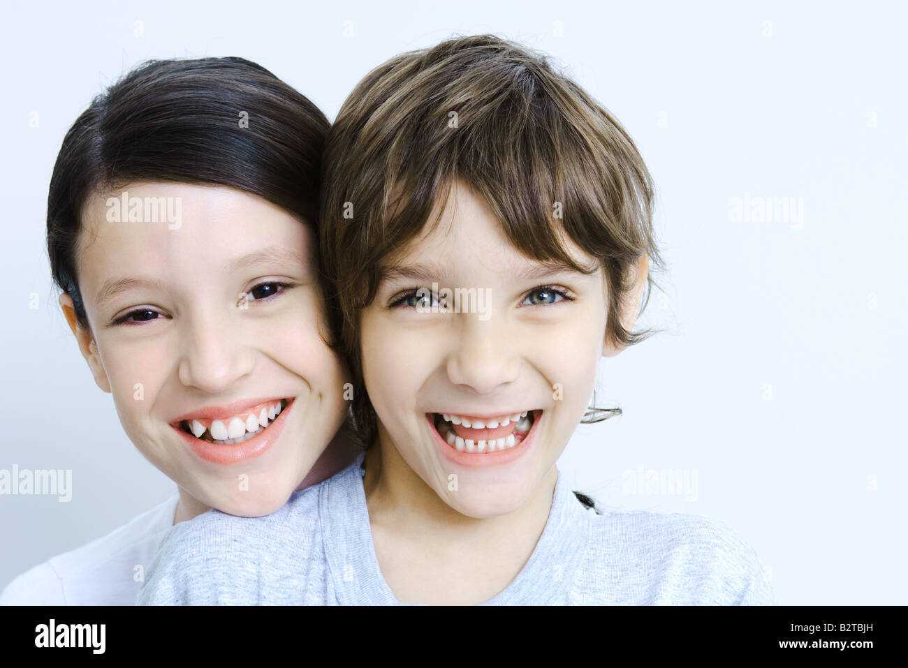 Sister behind her brother head resting on his shoulder, smiling at ...