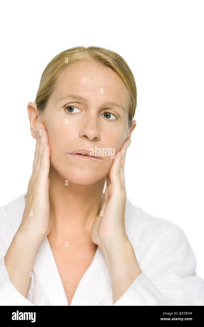 Mature woman touching face, looking away Stock Photo - Alamy