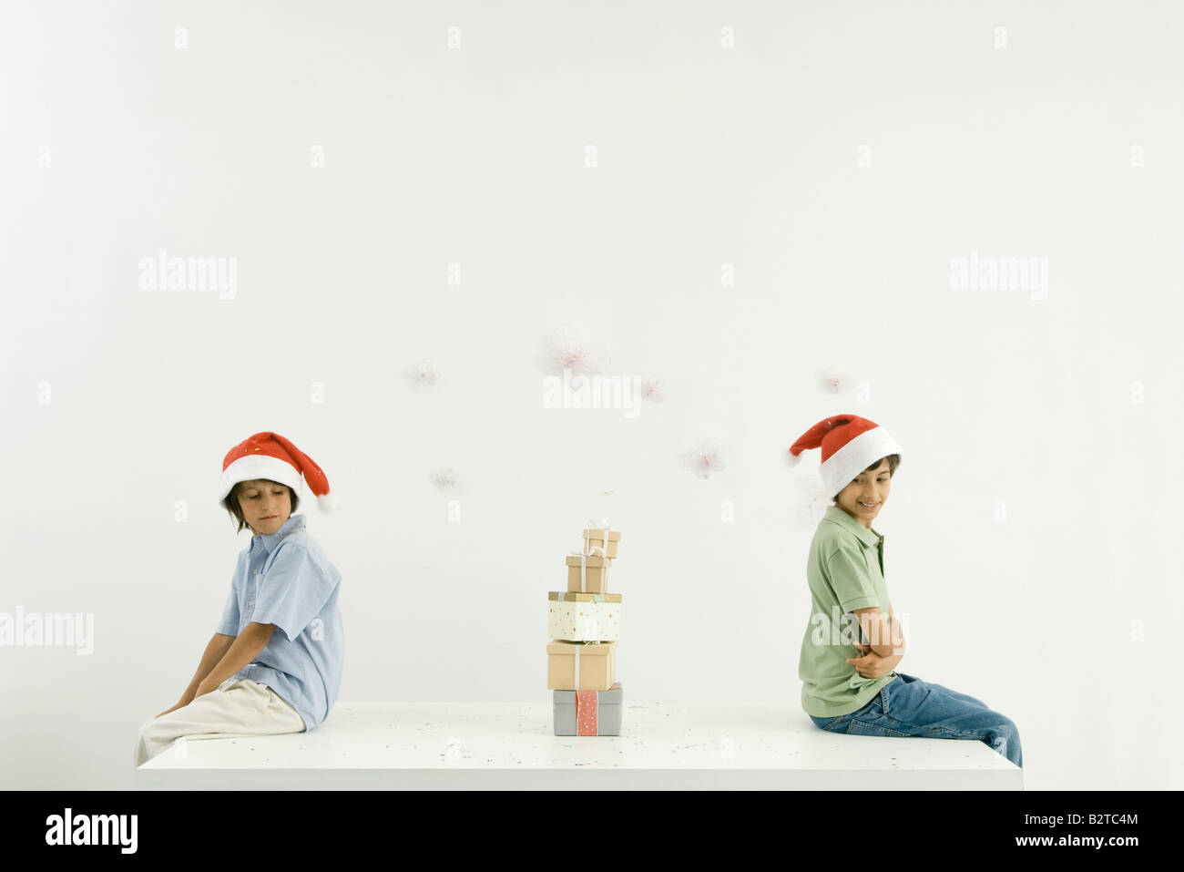 Two brothers sitting back to back, Christmas gifts stacked between them ...