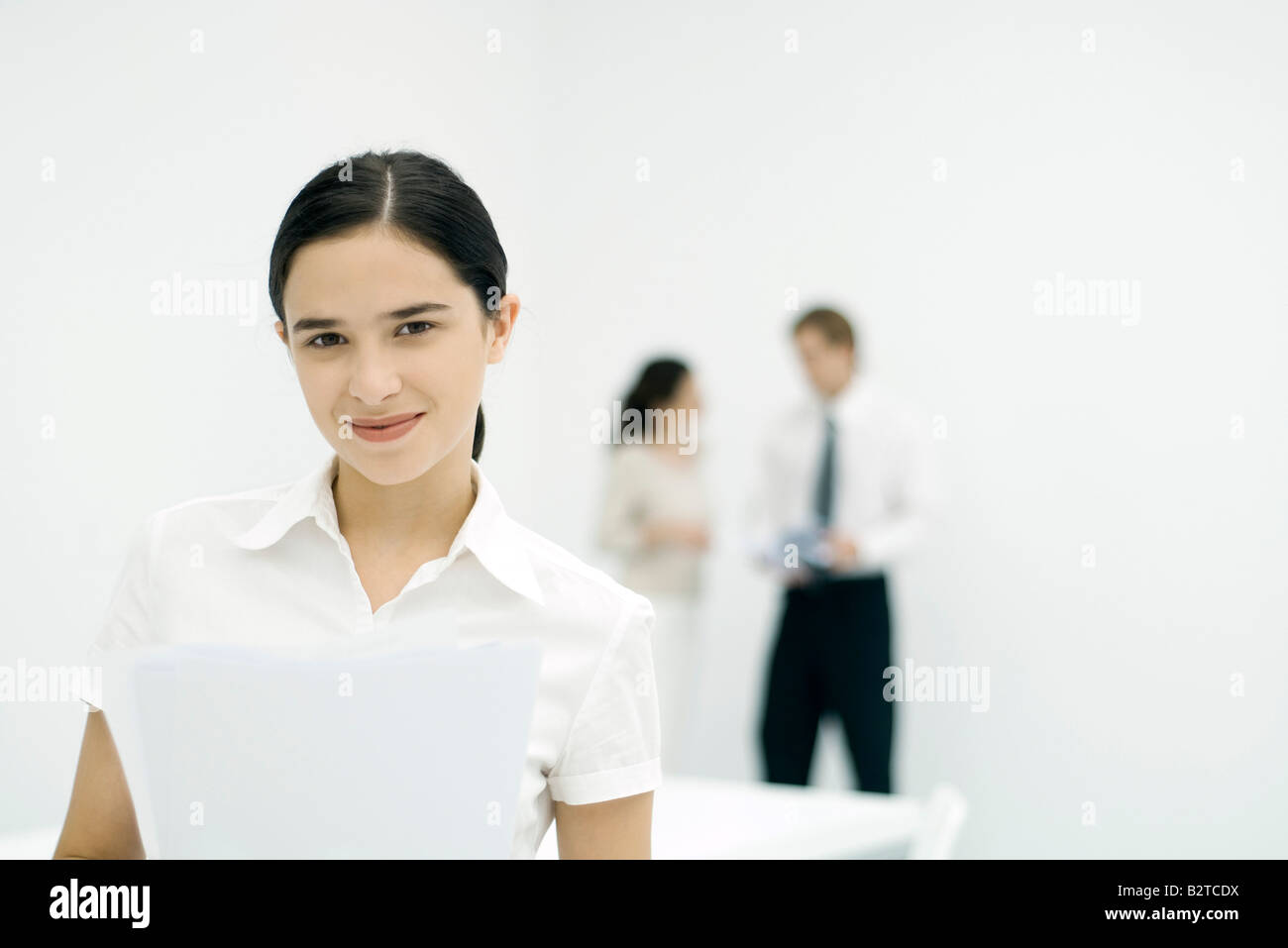 Female professional smiling at camera, colleagues in background Stock ...