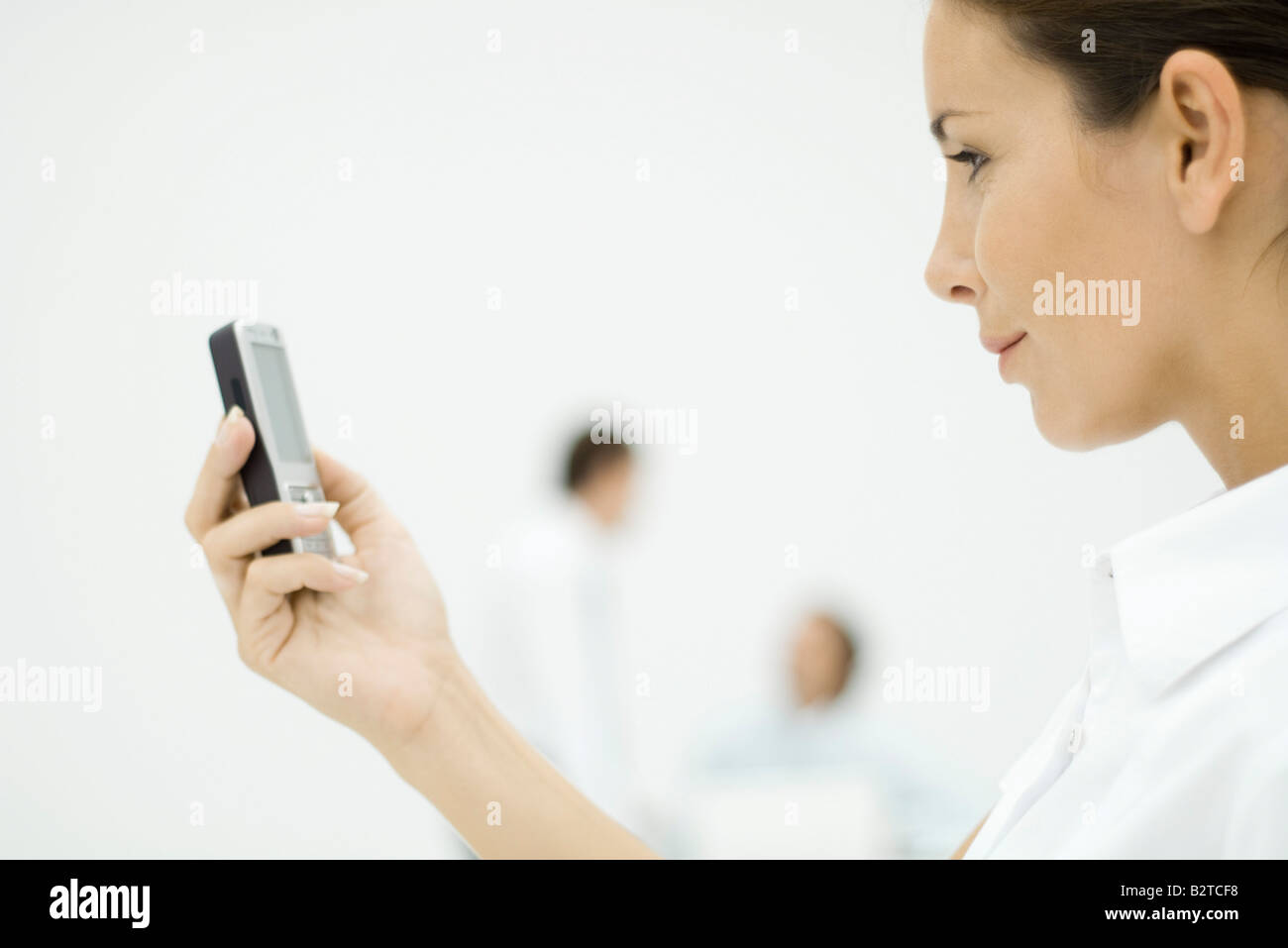 Woman looking at cell phone, side view, cropped Stock Photo - Alamy