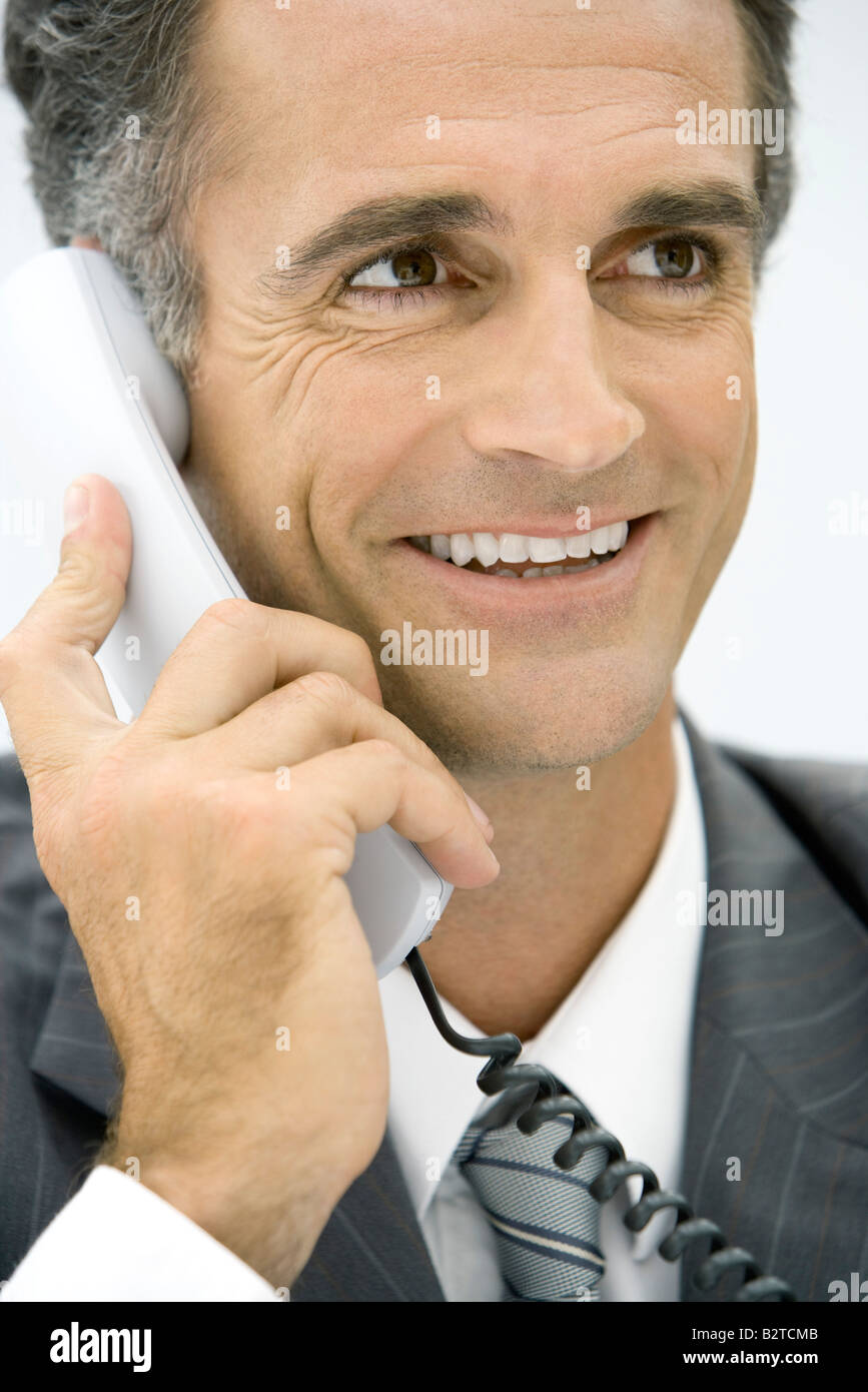 Man using landline phone, smiling, looking away Stock Photo - Alamy