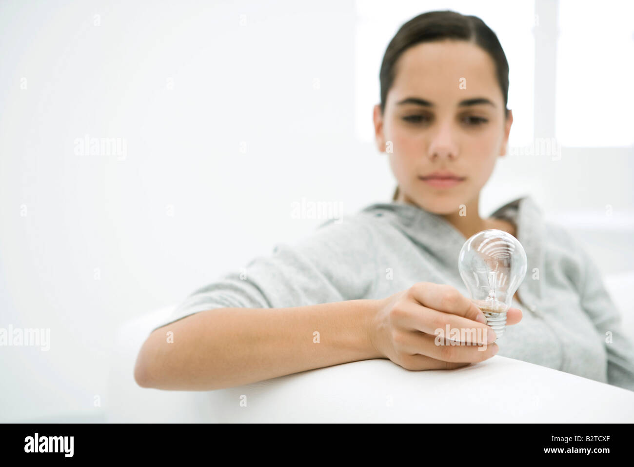 Teen girl looking at light bulb, focus on foreground Stock Photo - Alamy