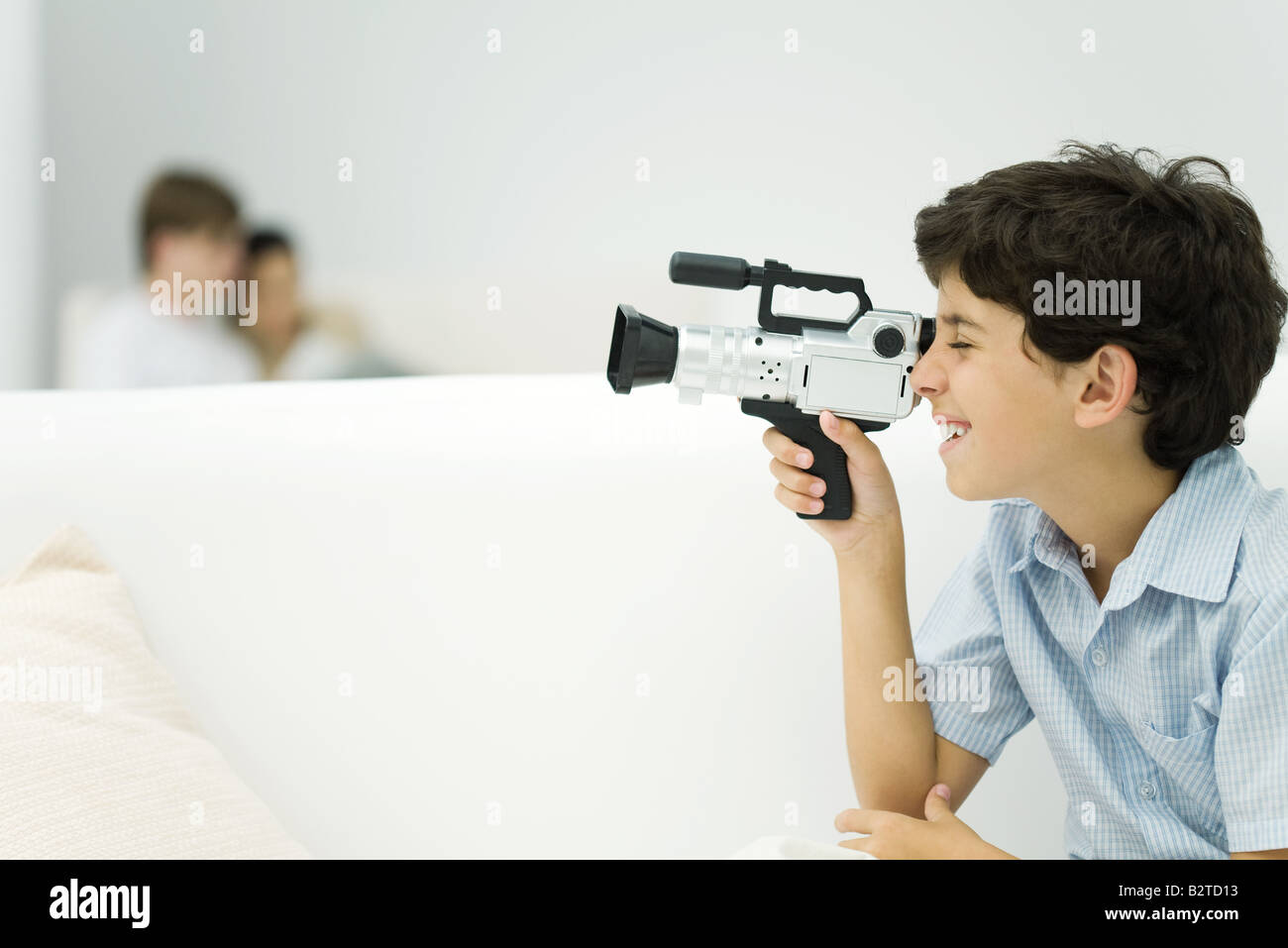 Boy looking through video camera, couple in background, side view Stock ...