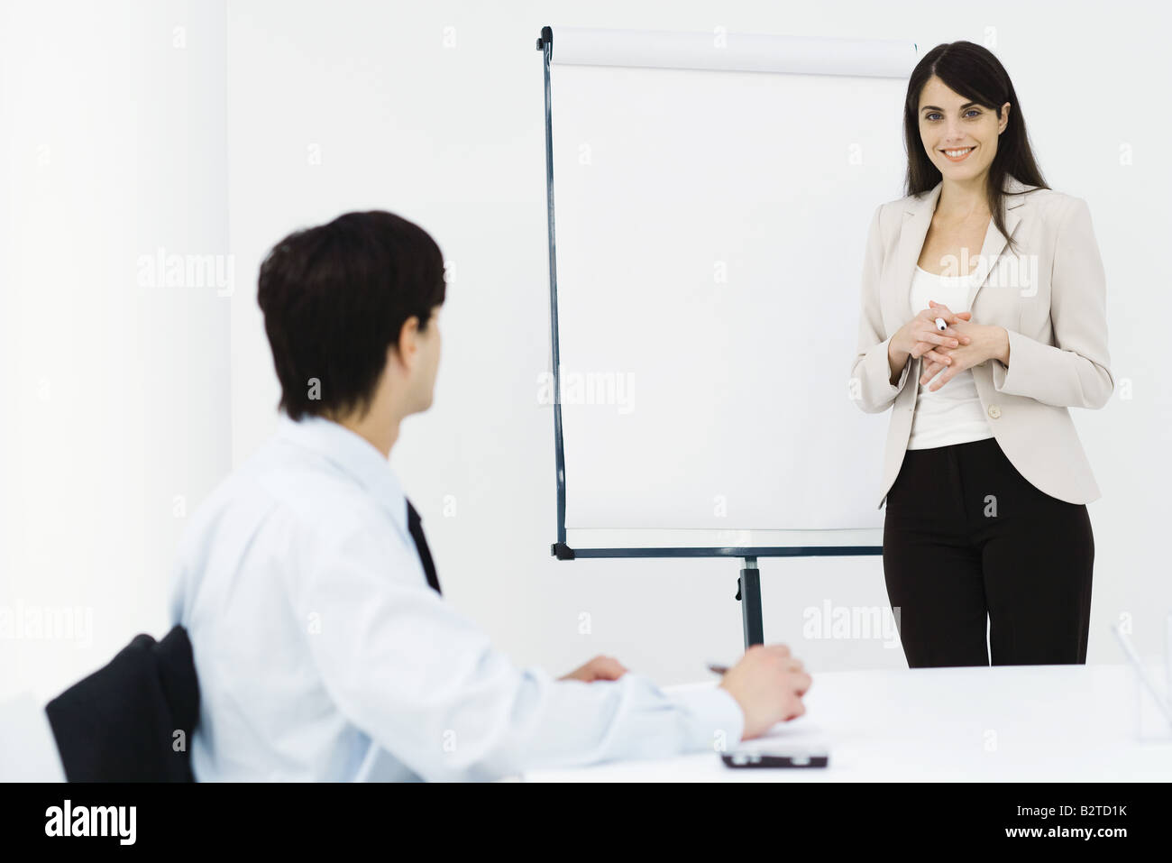 Woman standing in front of presentation board, smiling at camera, male ...