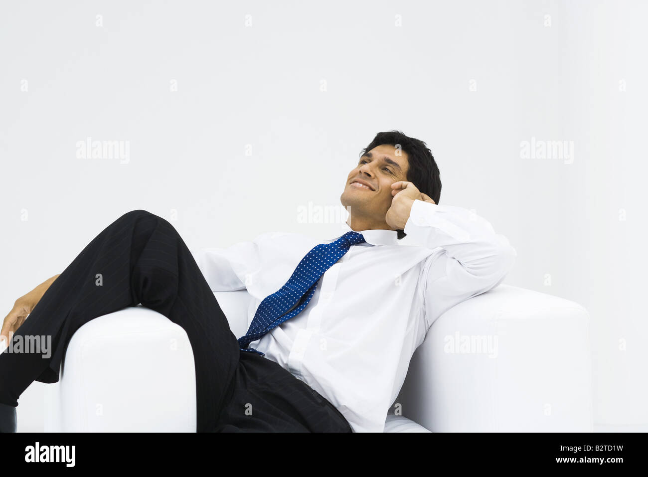 Man reclining in armchair, holding head, smiling Stock Photo - Alamy