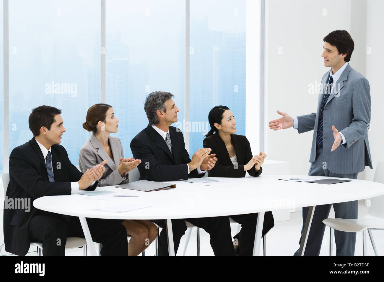 Business people applauding associate's presentation, sitting around ...