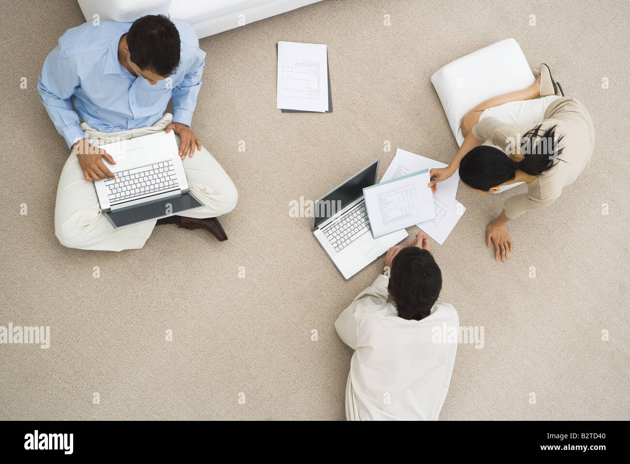 Business associates sitting together on floor, using laptop computers ...
