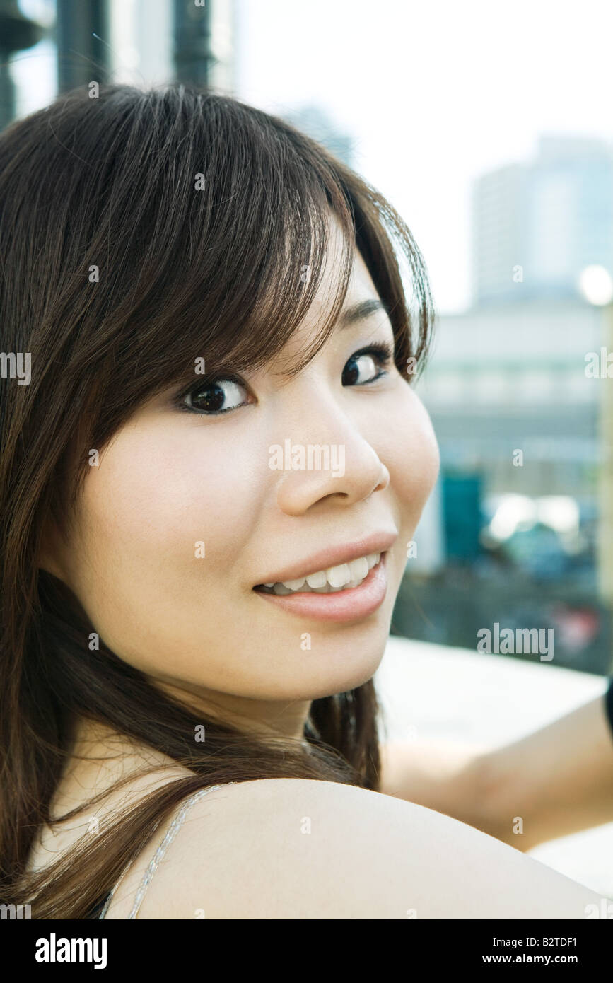 Young woman smiling over shoulder at camera, portrait Stock Photo - Alamy