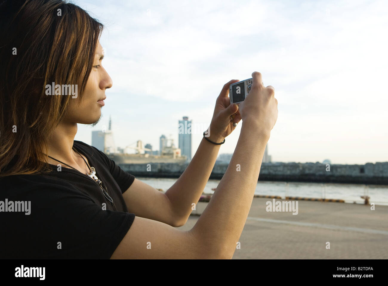 Young man photographing waterfront with digital camera, side view Stock ...