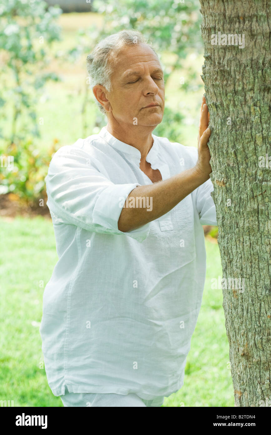 Mature man touching tree trunk, eyes closed Stock Photo - Alamy