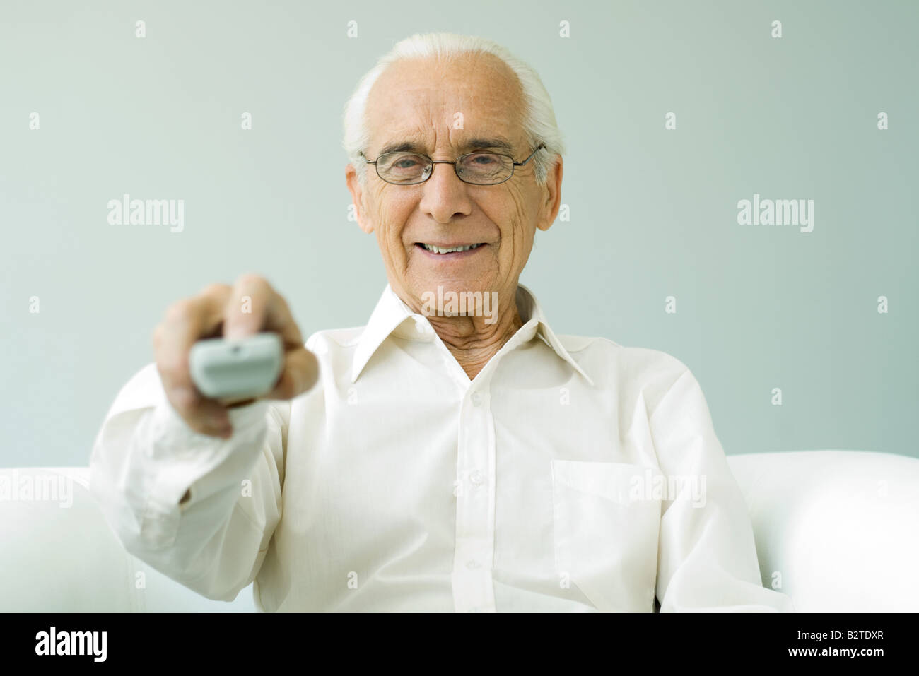 Senior man pointing remote control at camera, smiling Stock Photo - Alamy