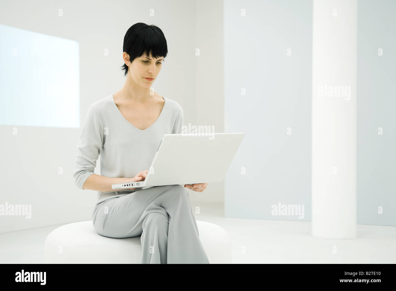 Woman sitting, holding laptop computer, looking down Stock Photo - Alamy