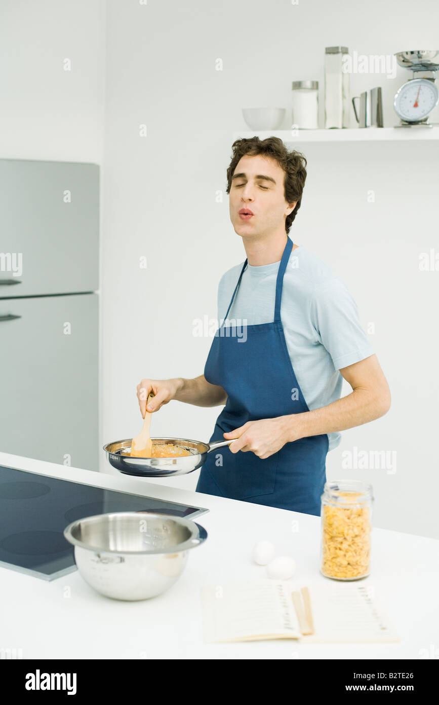 Man standing at stove, cooking, eyes closed, whistling Stock Photo - Alamy