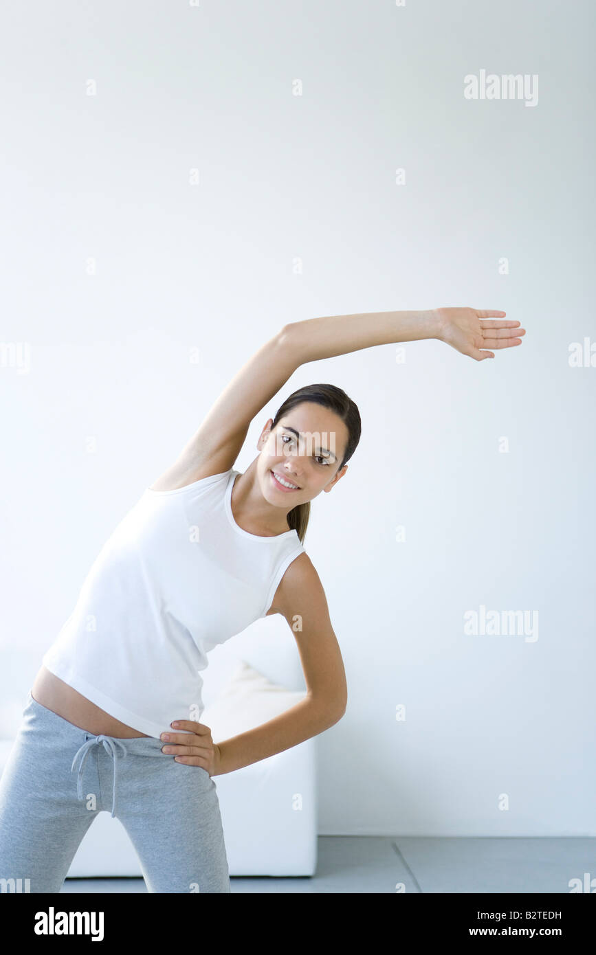 Woman stretching, one arm raised, smiling at camera Stock Photo - Alamy