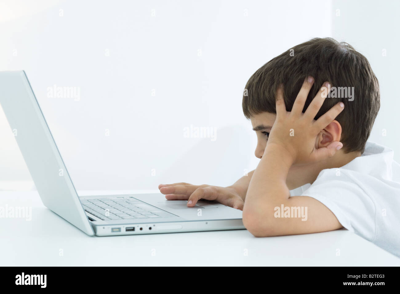 Little boy using laptop computer, holding head, side view Stock Photo ...