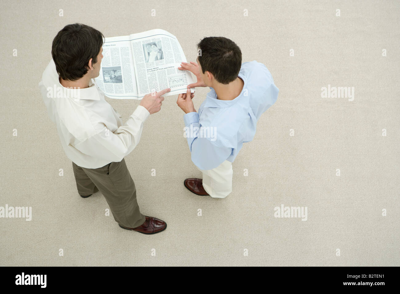 Two men looking at newspaper together, overhead view Stock Photo - Alamy