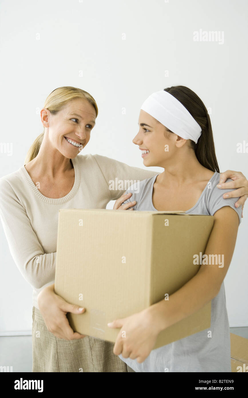 Mother with arm around daughter's shoulder, daughter holding cardboard ...
