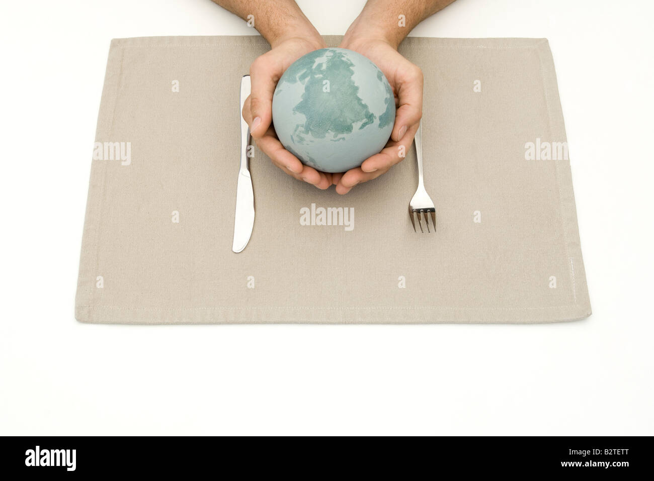 Hands holding globe over placemat and silverware Stock Photo - Alamy