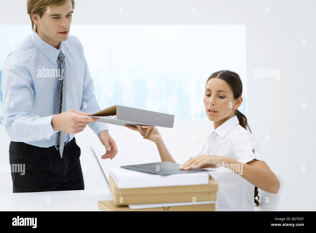 Professional woman handing binder to colleague from stack of many ...